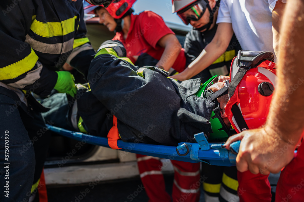 Firefighter and ambulance workers taking care of other firefighter and ...