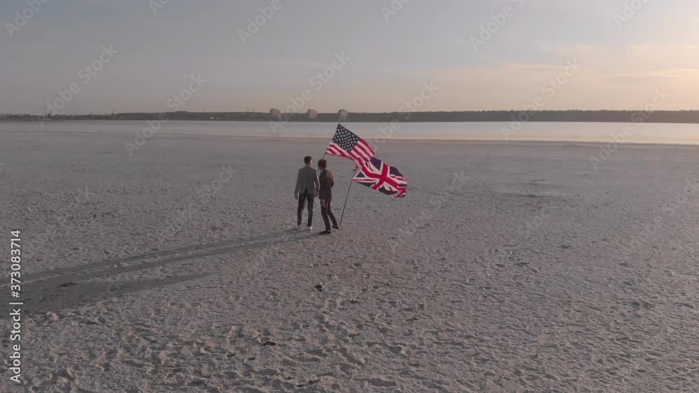 Two men insert flagpoles with the flags of the United States and Great ...
