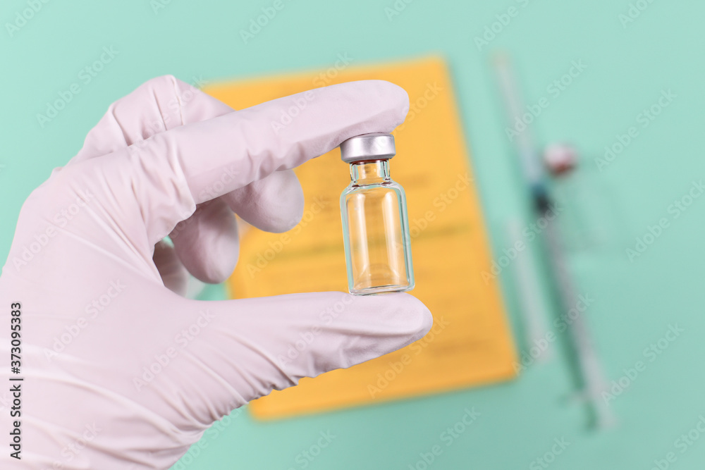 Vaccine concept with hand with medical glove holding empty vial and ...