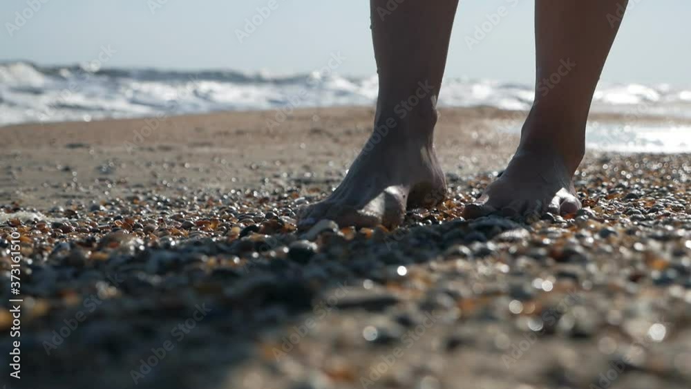 Barefooted woman tourist walks on sea shells on sand beach makes nature ...
