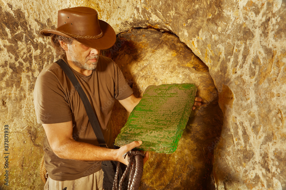Adventurer in ancient cave on trace of mysterious emerald tablet ...