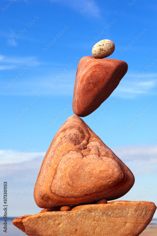 The fall of the pyramid of balanced stones on blue sky background. The ...