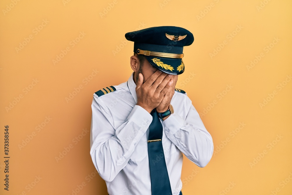 Handsome hispanic man wearing airplane pilot uniform with sad ...