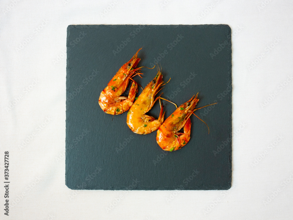 Grilled shrimp on a square black slate plate. Grilled shellfish on ...