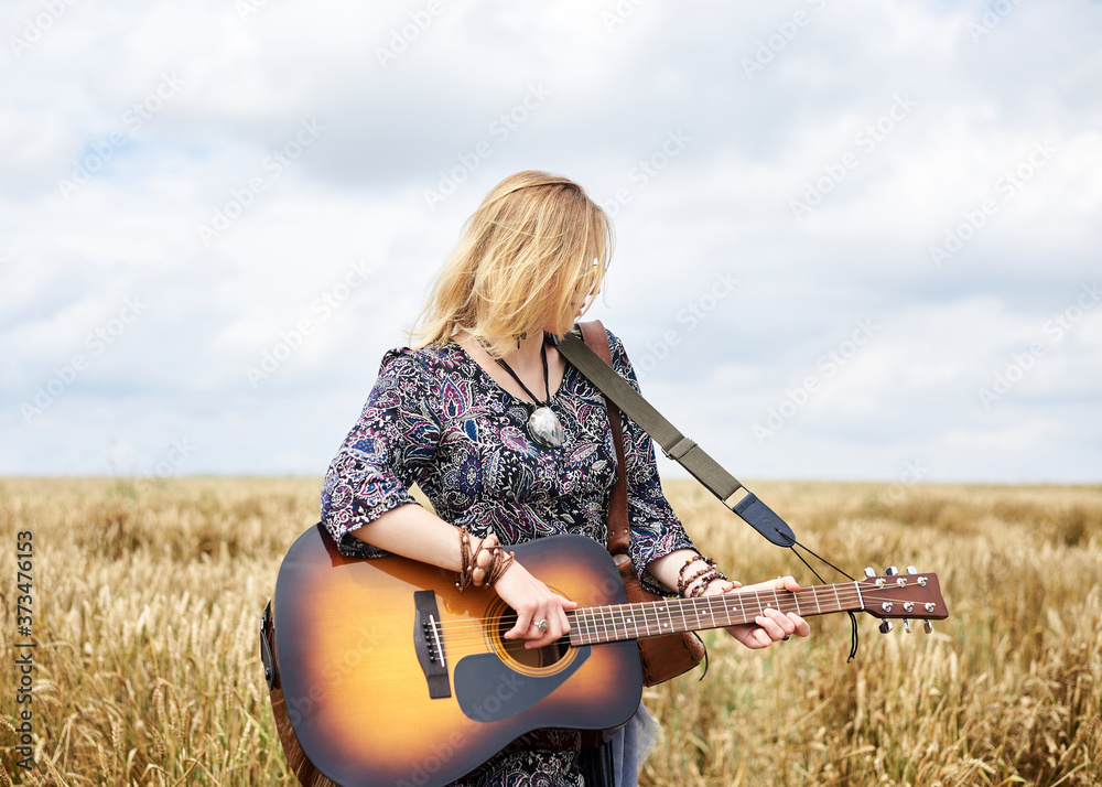 Young blond skinny hippie woman, wearing boho style clothes, playing ...
