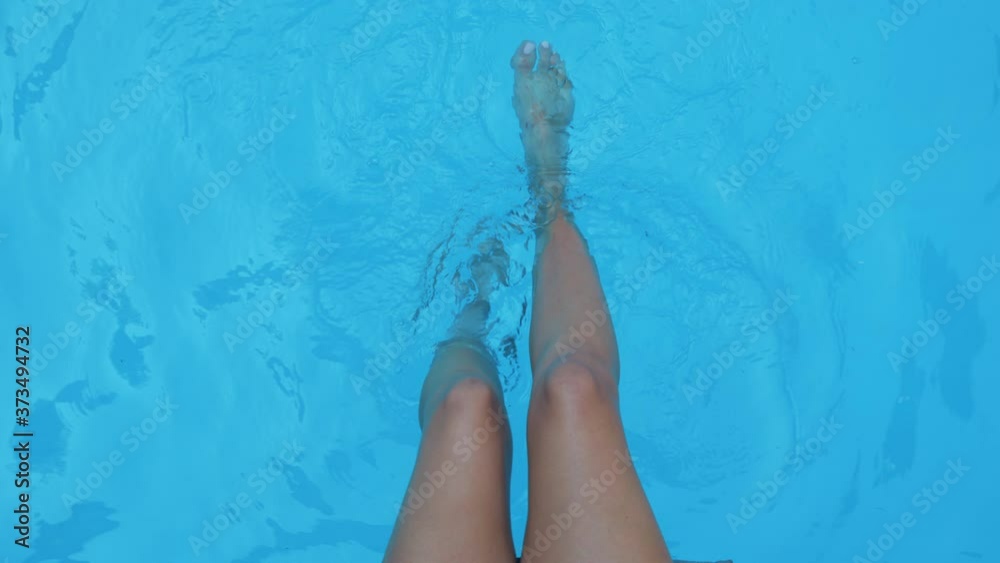 Close up shot of suntanned female legs swinging shaking making splash ...