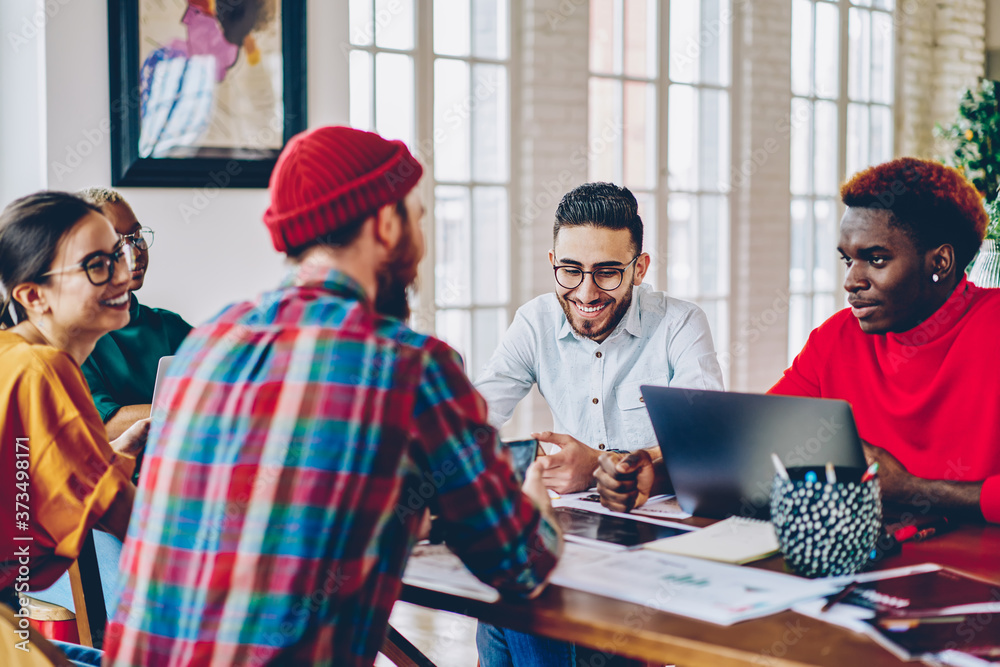 Crew of multiracial colleagues enjoying positive discussion during ...
