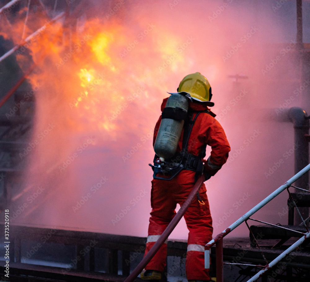 Firefighters using water fog spraying down fire from oil rig factory ...