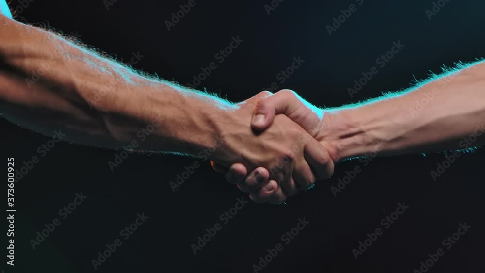 Handshake of two men with bare hands. Shot against black background ...