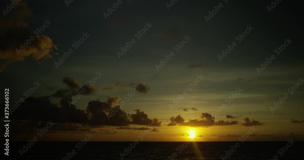Beautiful sunset dipping below horizon line with dramatic clouds and ...