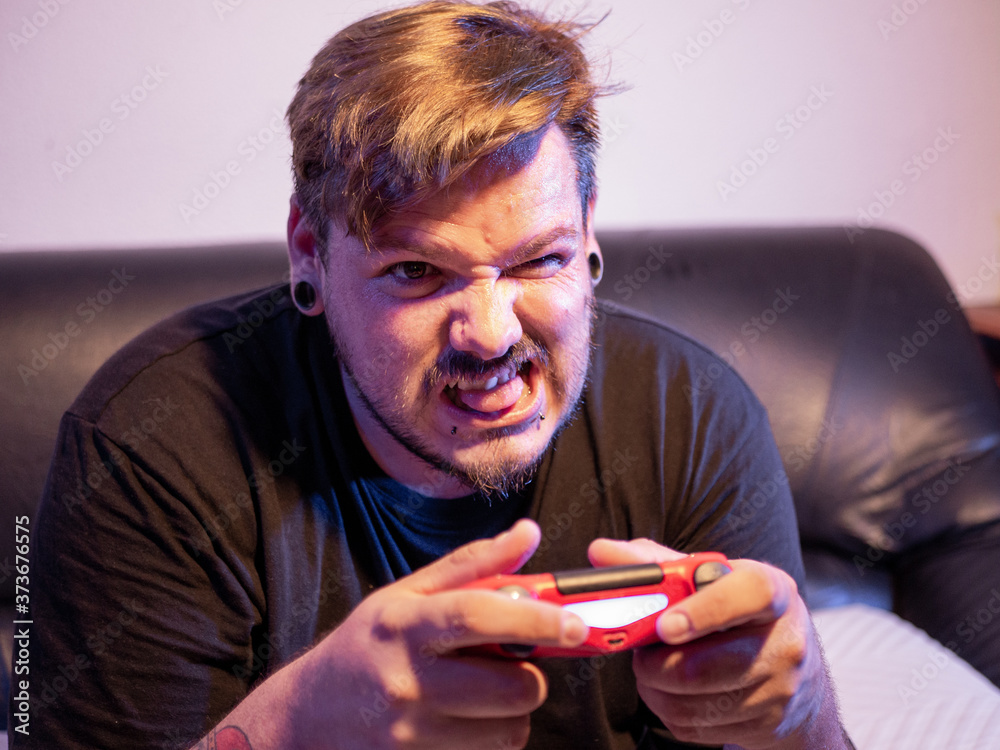 Hombre joven con tatuajes enfadado jugando videojuegos en el salón de ...
