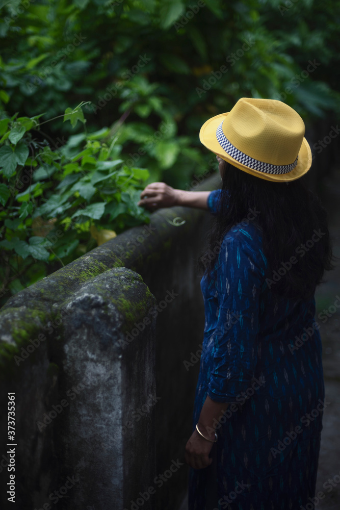 Backside view of an Indian woman standing on garden fencing wearing a ...
