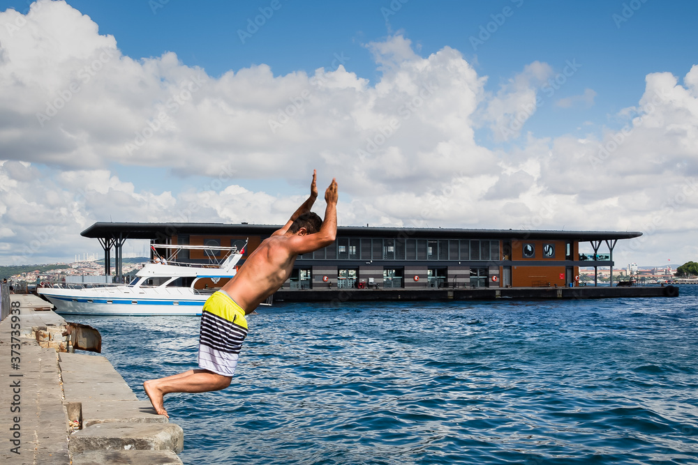 Young turkish man jumping in the sea from the pier of Karakoy on a hot ...