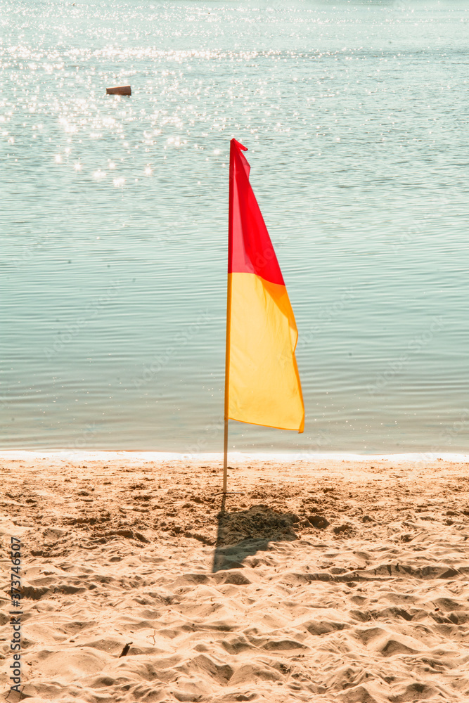 Fotka „Flag on the river bank for permission to swim in the water ...
