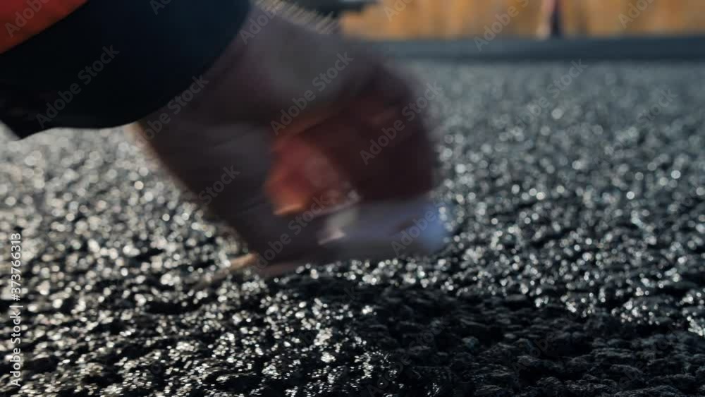 Measuring the temperature of fresh asphalt. Close-up of a man's hand ...