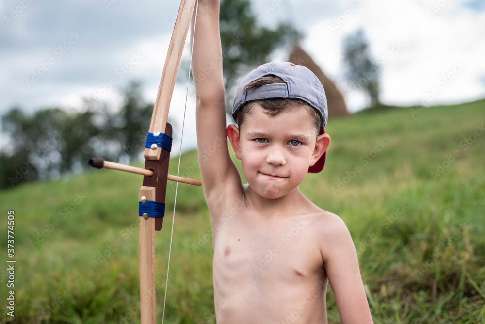 A young boy with a brave face and a bow with an arrow in his hands, a ...