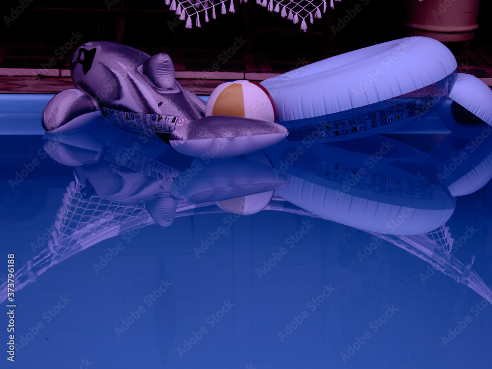 ball and plastic floats pushed by the wind to the edge of a pool with ...