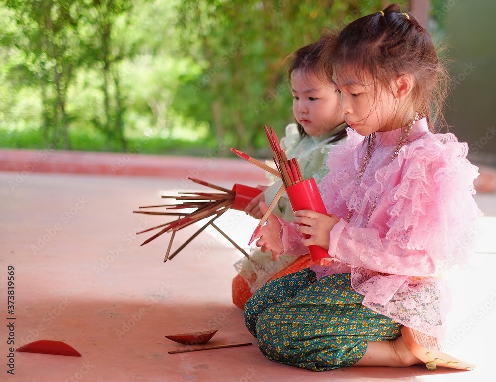 Foto de Cute young Asian girls in traditional Thai costumes are shaking ...