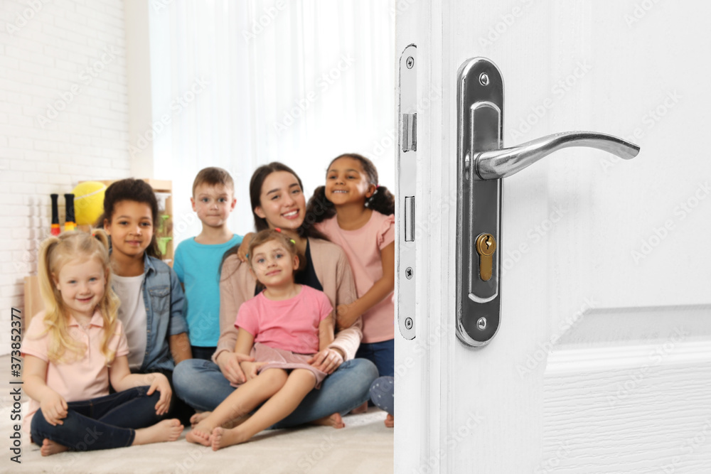 Wooden door open into modern classroom with teacher and children Stock ...
