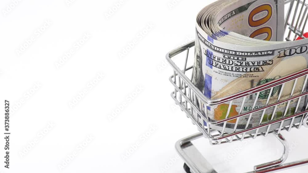 Hand pushing miniature toy supermarket trolley. In a cart a bundle of ...