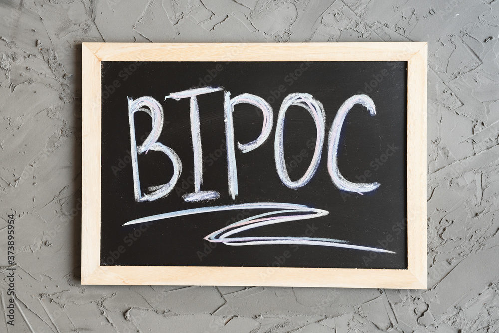 BIPOC acronym written on a small blackboard, concrete wall as ...