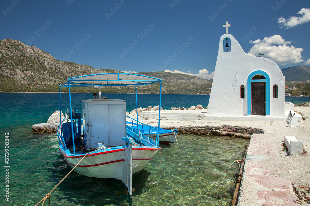 Kapelle und Fischerboot am See von Vouliagmeni, Korinthia, Griechenland. Stock Photo | Adobe Stock