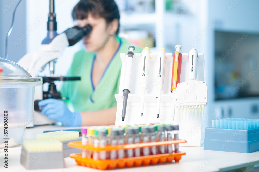 Female professional in uniform. Work with a light microscope in a ...