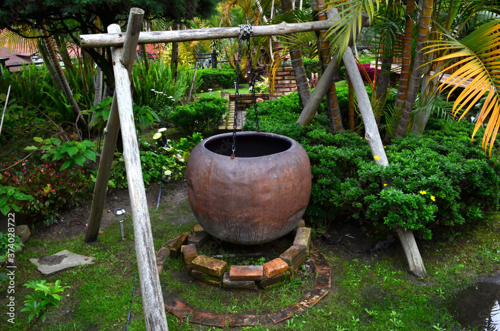 Large clay cauldron hung on wooden stick structure, over a brick fire ...