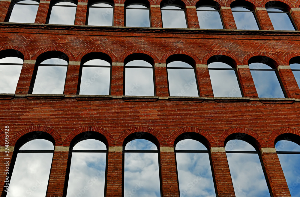 Symmetrical windows with sky reflection on the brick wall of the ...