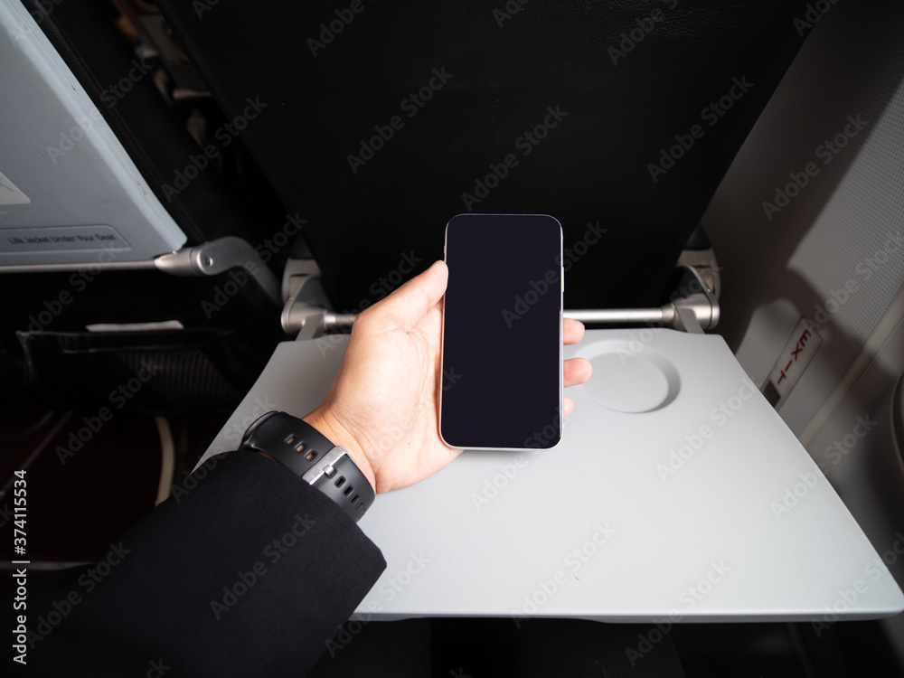 Holding mobile smart phone on aircraft seat next to window. Aircraft ...