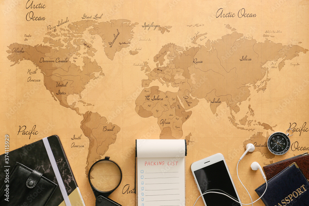 Notebook with check-list of things to pack for travel on world map ...