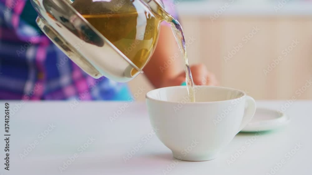 Green tea flowing from teapot in slow motion. Close up of tea from the ...
