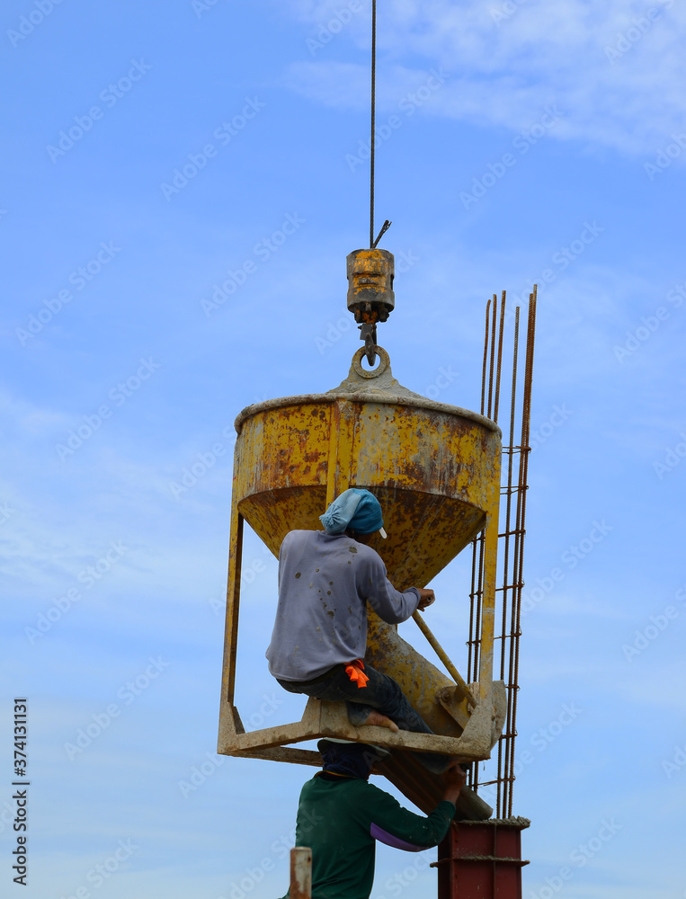 Crane is lifting buckets of cement up to the high lime water to pour ...