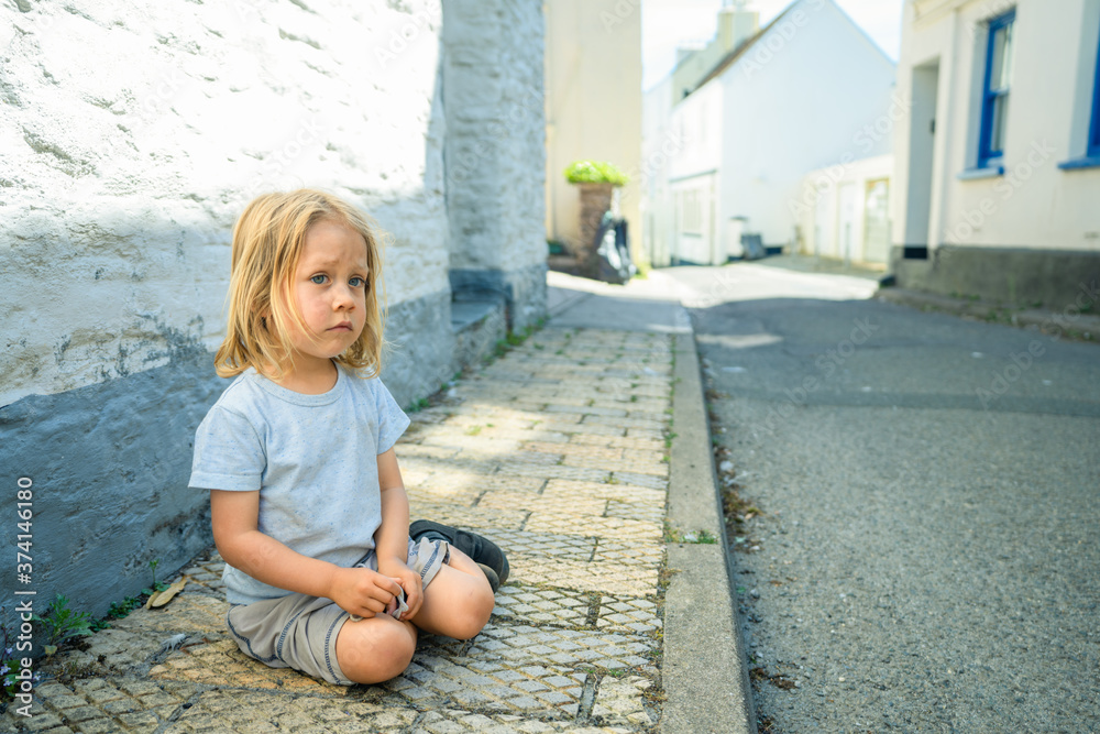 Little preschooler sitting on the pavement in a town Stock Photo ...