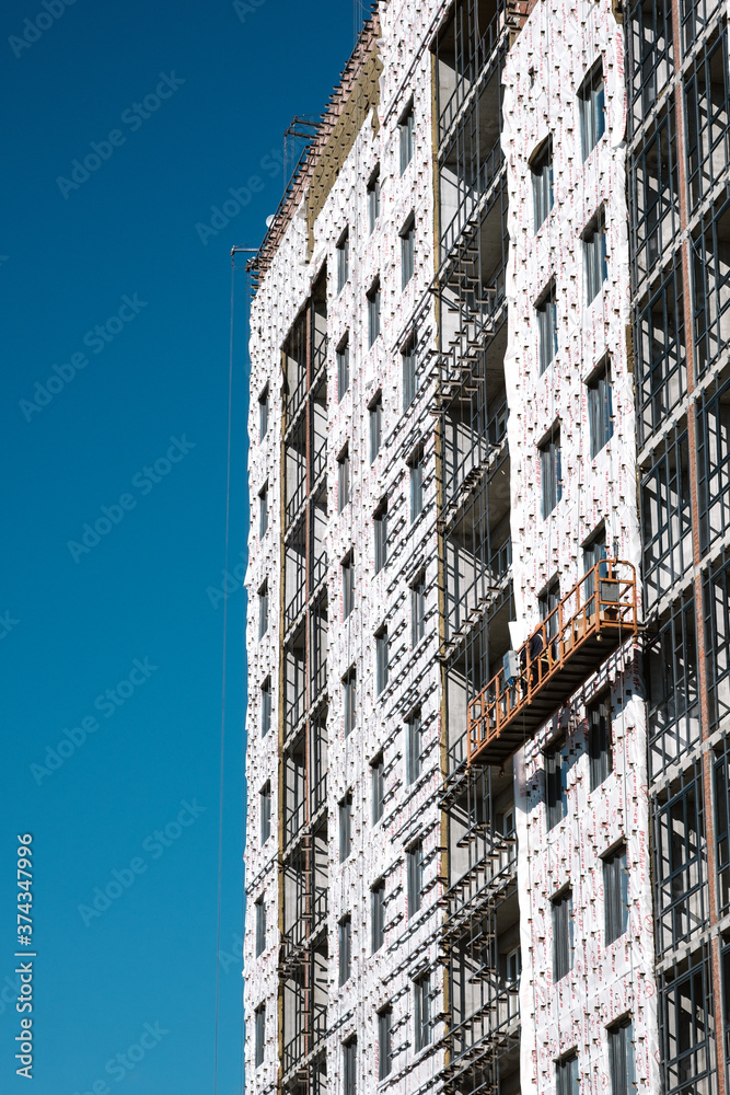 Builders on an industrial elevator are engaged in cladding and ...