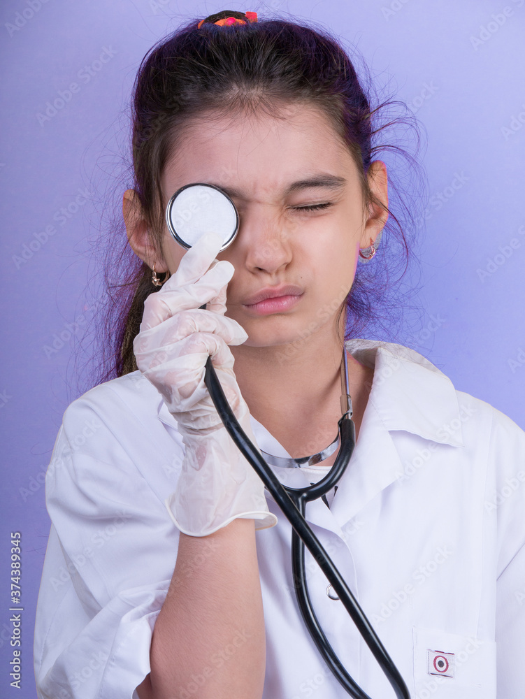 Little funny girl with a stethoscope and gloves while wearing Doctor's ...