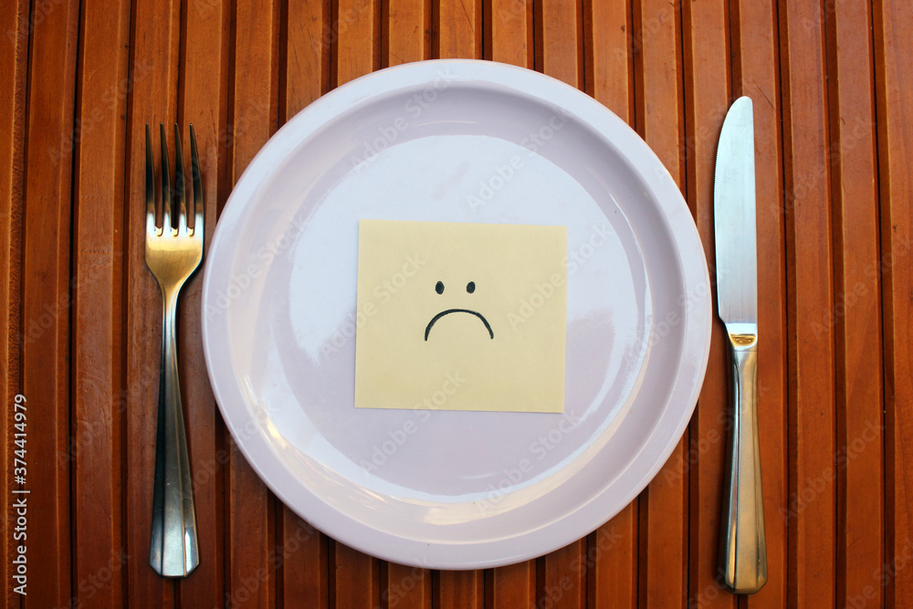Empty plate with sad face draw in the middle. Stock Photo | Adobe Stock