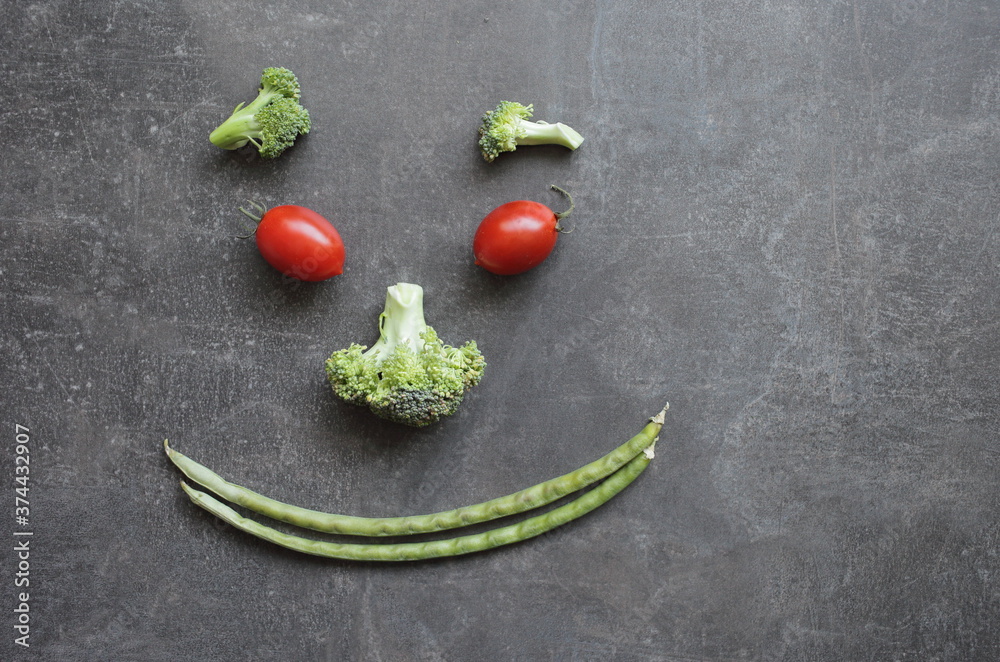Smiling emoticon of fresh vegetables cherry tomatoes broccoli and green ...