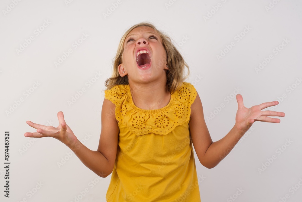 Young blonde kid girl wearing yellow dress over white background crazy ...