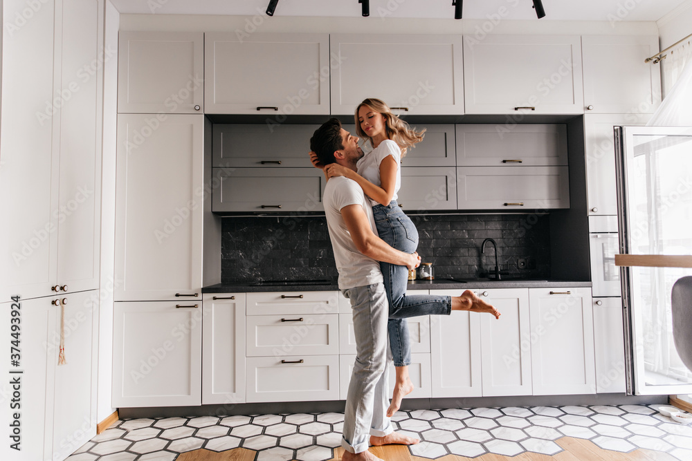 Shapely curly girl dancing with husband in kitchen. Indoor photo of ...