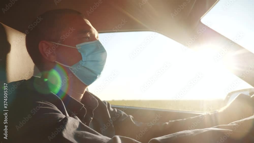 worker driver wearing medical mask drives a car during the coronavirus ...