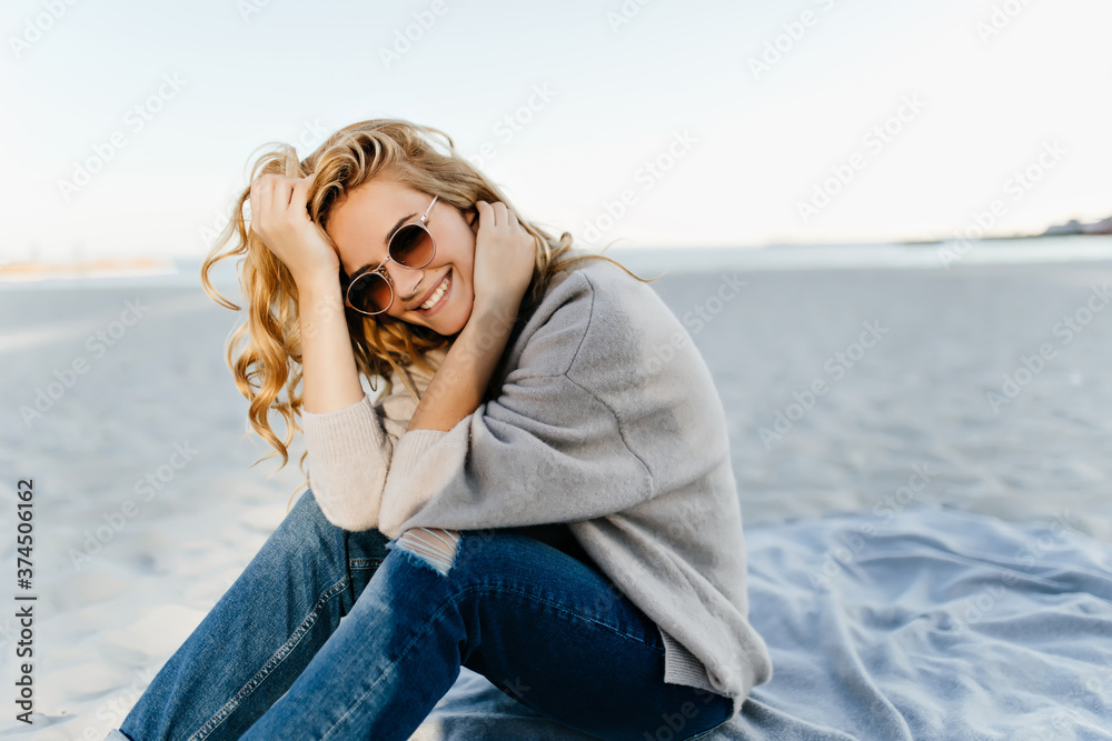 Jocund woman in dark sunglasses chilling at beach in cold morning ...
