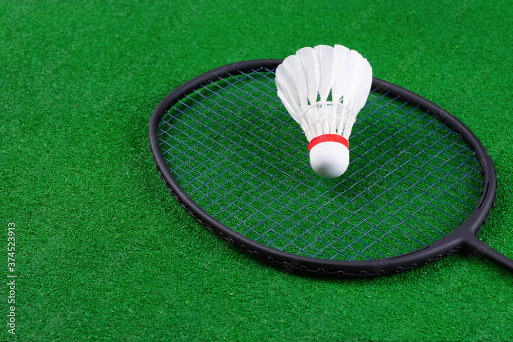 Selective focus shot of shuttlecock and badminton racket on a green ...