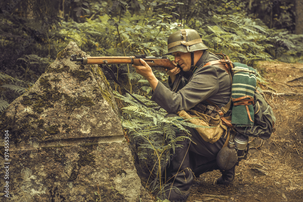 A soldier of world war II, firing a rifle from behind a granite chasm ...