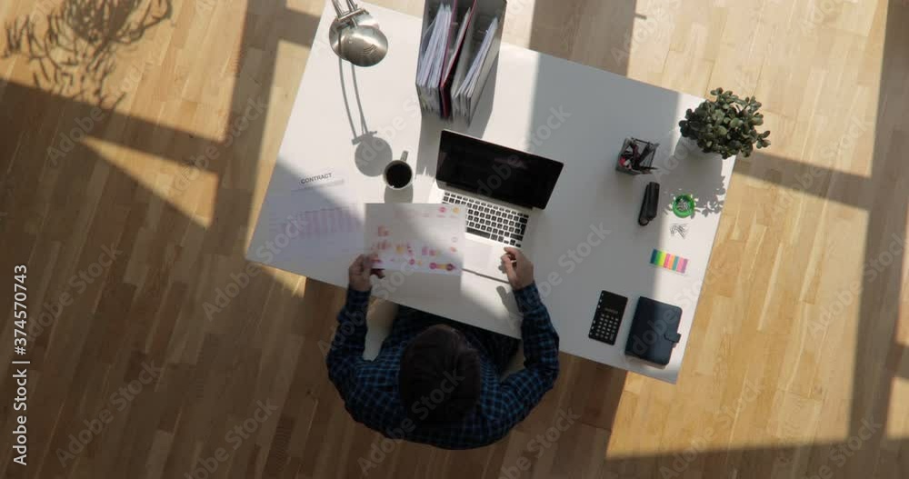 Spinning top view shot of an office worker sitting on desk looking at ...