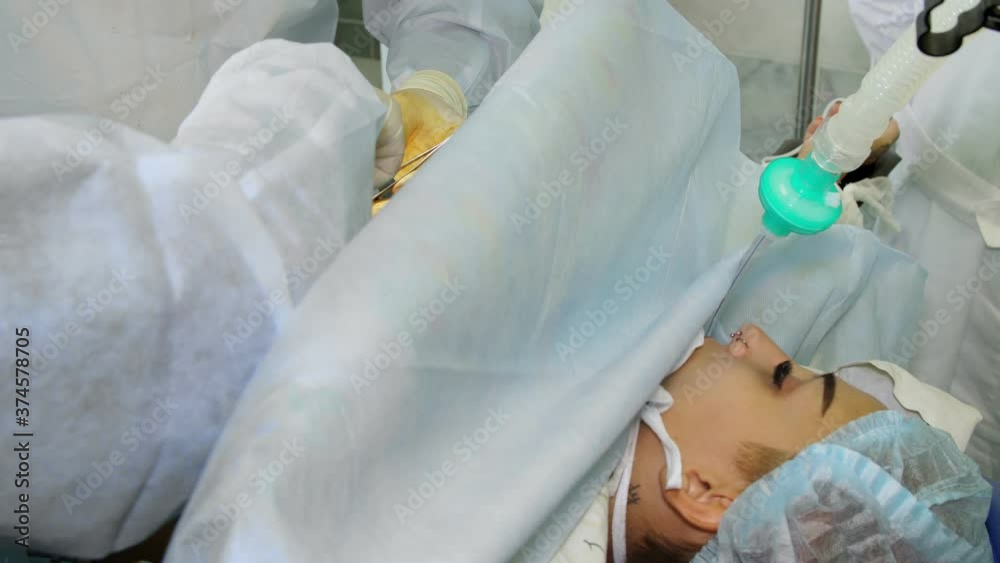 close-up. surgeon and his assistant suture the incisions under the ...