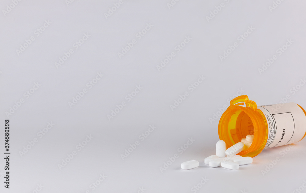 pill bottle lying on its side with white tablet pills spilling out on a ...
