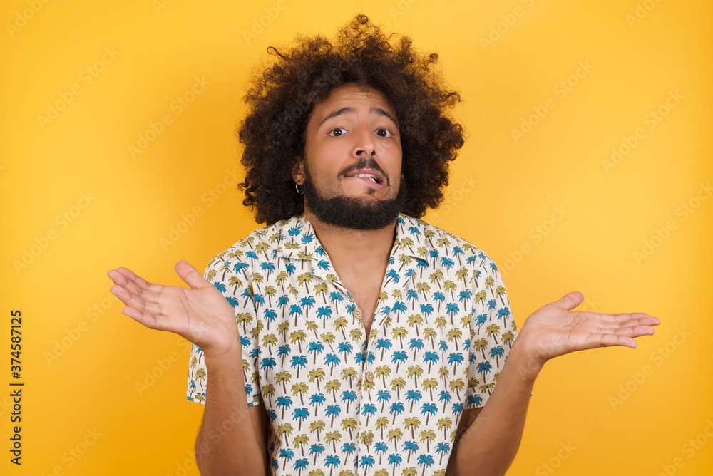 Clueless Young man with afro hair over wearing hawaiian shirt standing ...