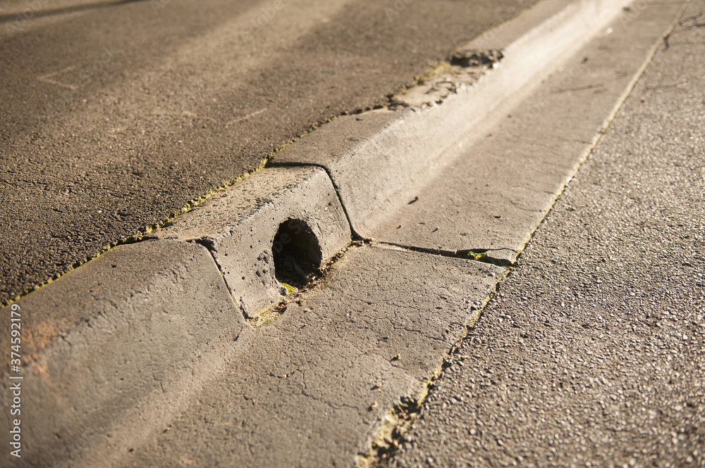 Gutter of a stormwater drainage system in perspective on the side of an ...