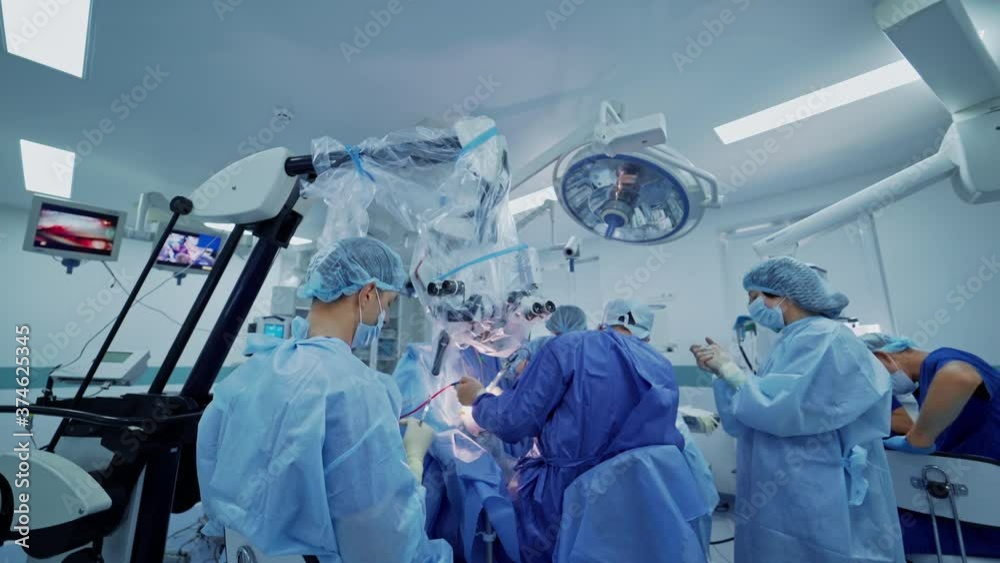 Modern microscope in surgical room. Group of doctors conduct a ...